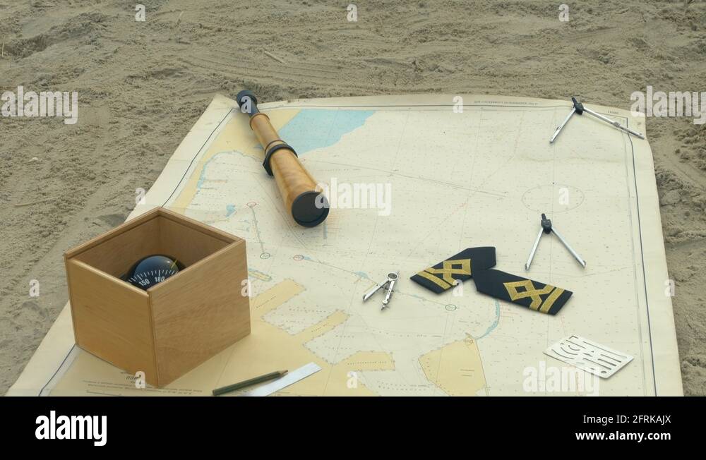 Navigational instruments, chart on sand. Granite rocks. Metall pier ...