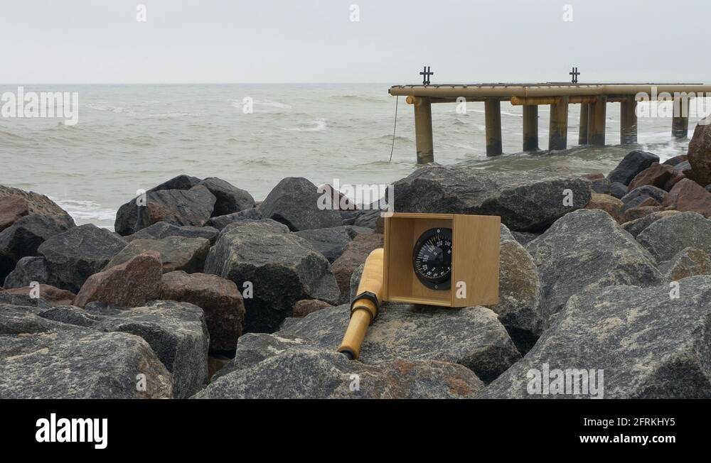 Compass and telescope spyglass on granite rocks. Metall pier, bollard ...