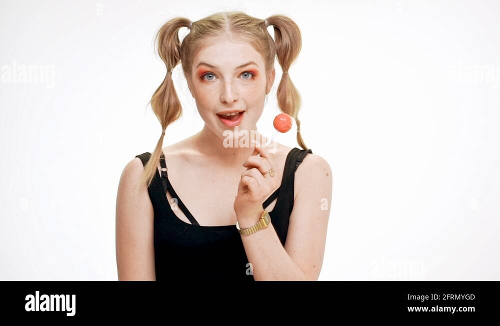 Young beautiful girl dancing, smiling, eating chupa chups over white ...