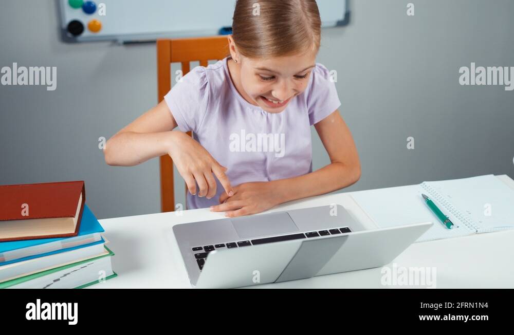 School girl child 7-8 years using her laptop in her desk in classroom ...
