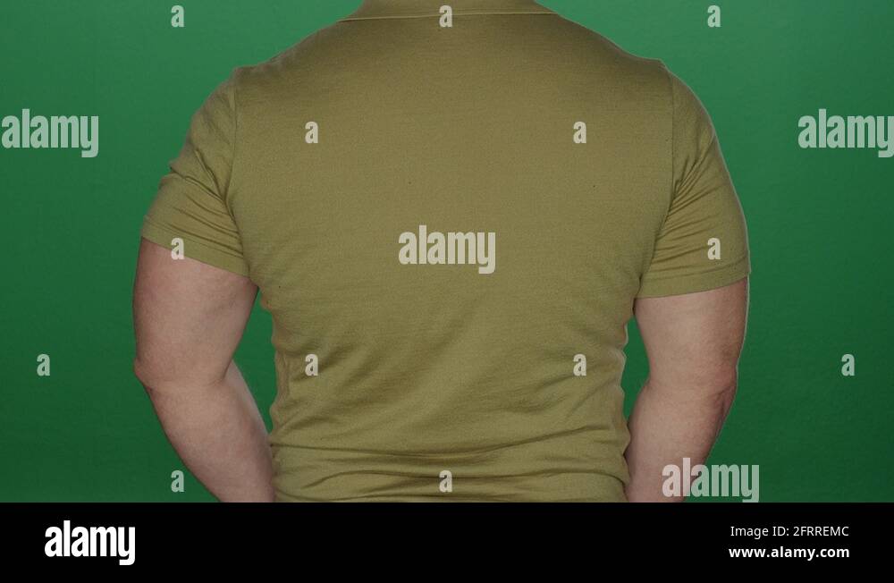 muscular man looks over his shoulder, on a green screen background ...
