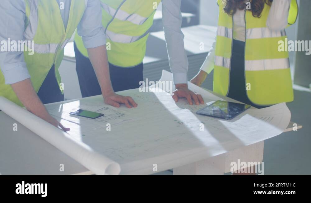 Team of Engineers are Bending over Large Blueprint and Having ...