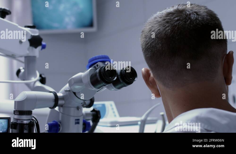 Dentist looks through the microscope at sealing of tooth canals Stock ...
