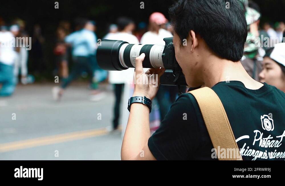 Photographer takes photos of a large crowd of people running a street ...