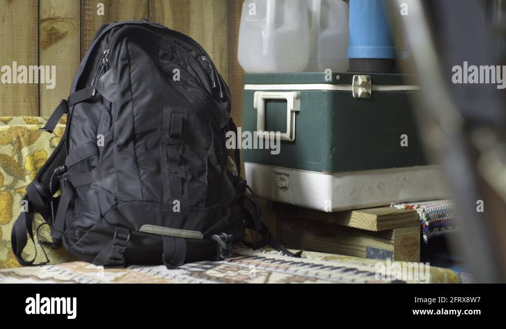 A older hiker grabbing backpack from inside a cabin in the woods Stock ...
