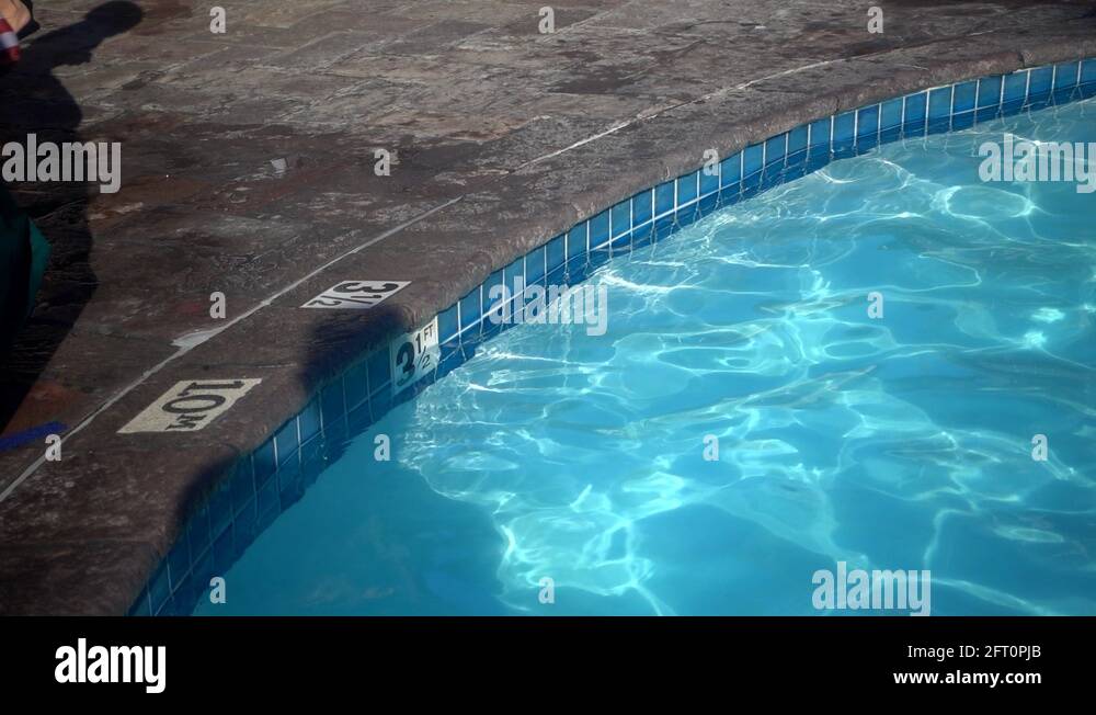 A boy doing a cannonball and jumping into a pool at a hotel resort ...