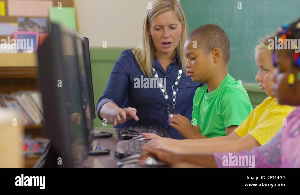 Teacher and student working on computers in school classroom Stock ...