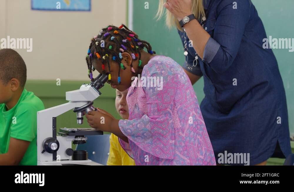 Teacher and students look through microscopes in school classroom Stock ...