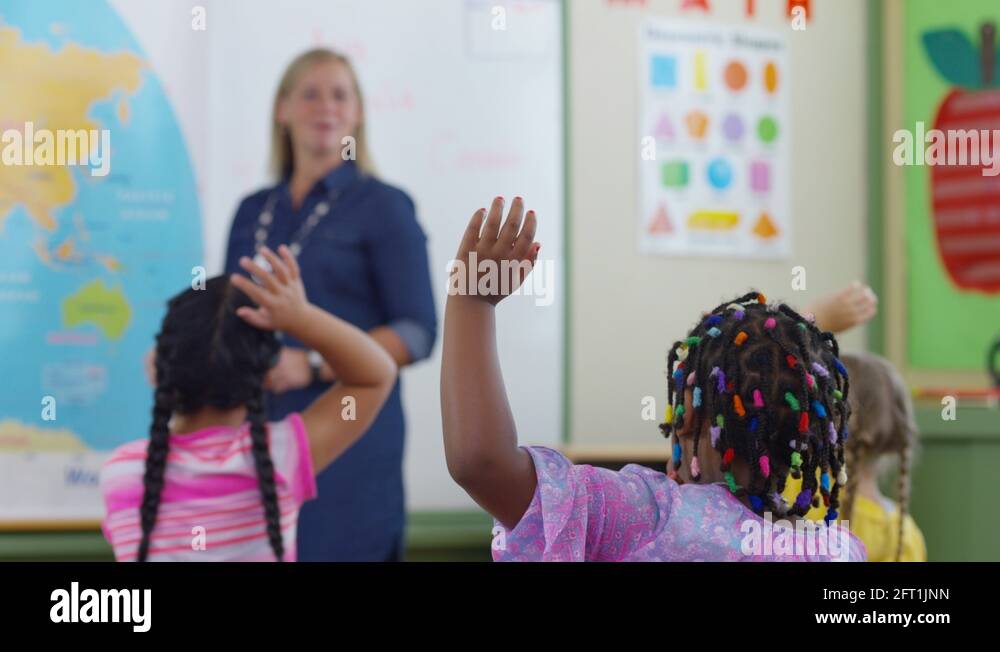Teacher gives lesson in school classroom and students raise hands, rack ...