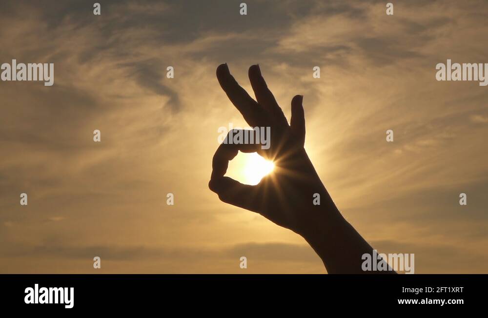 CLOSE UP, DOF: Connecting thumb and index finger in circle over shining ...