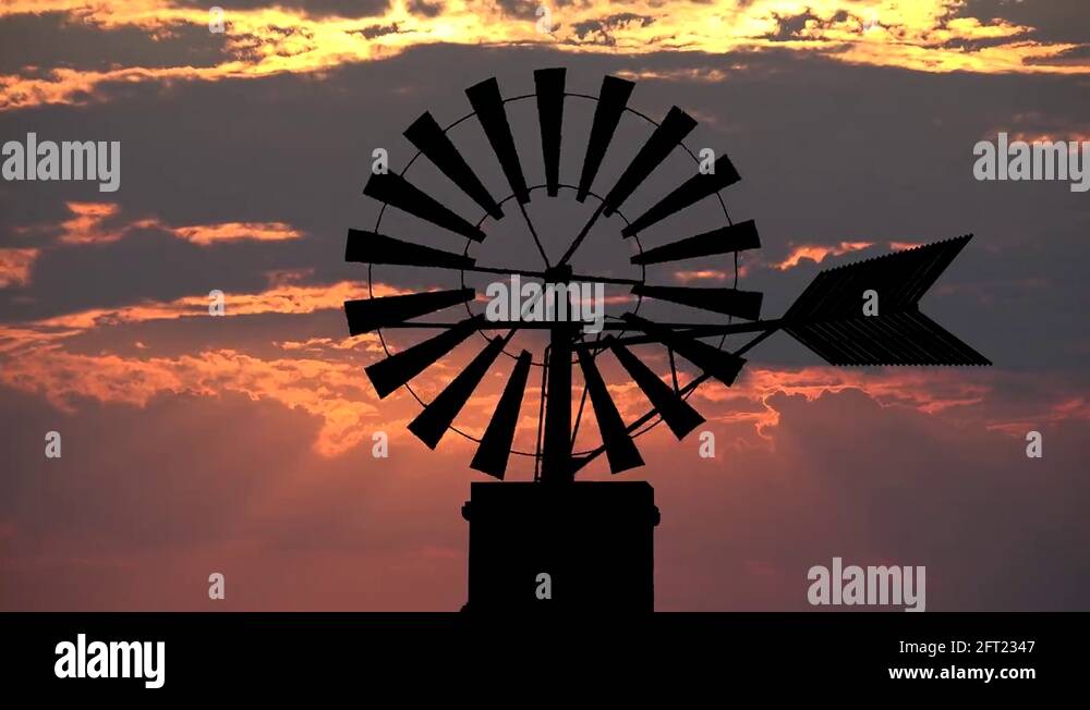 Traditional rustic old windmill spinning silhouette and sunset red ...