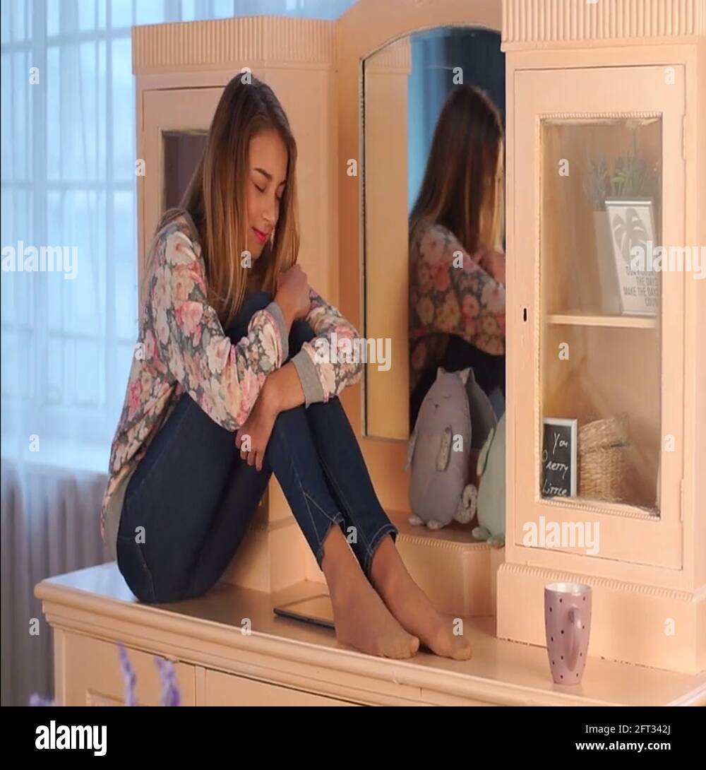 young beautiful teenage girl sitting on commode in the living room ...
