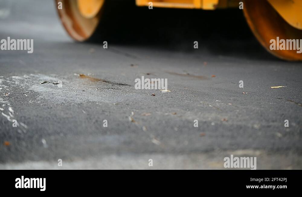 Asphalt paving with a steel wheel roller. Steam coming out from asphalt ...