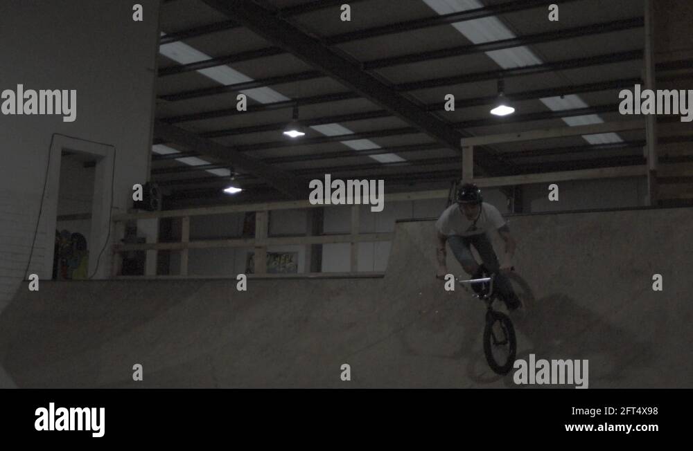 A boy rides a BMX bike on an indoor skate park half pipe ramp Stock ...