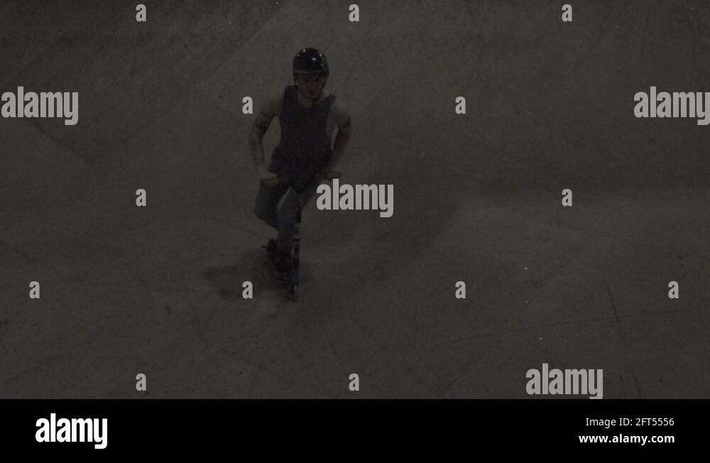 A boy rides his scooter on an indoor skate park half pipe ramp Stock ...