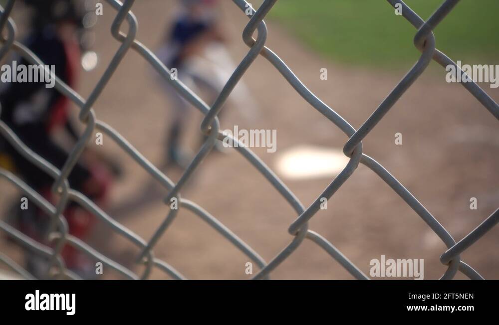 Boys playing in a little league baseball game through a chain-link ...