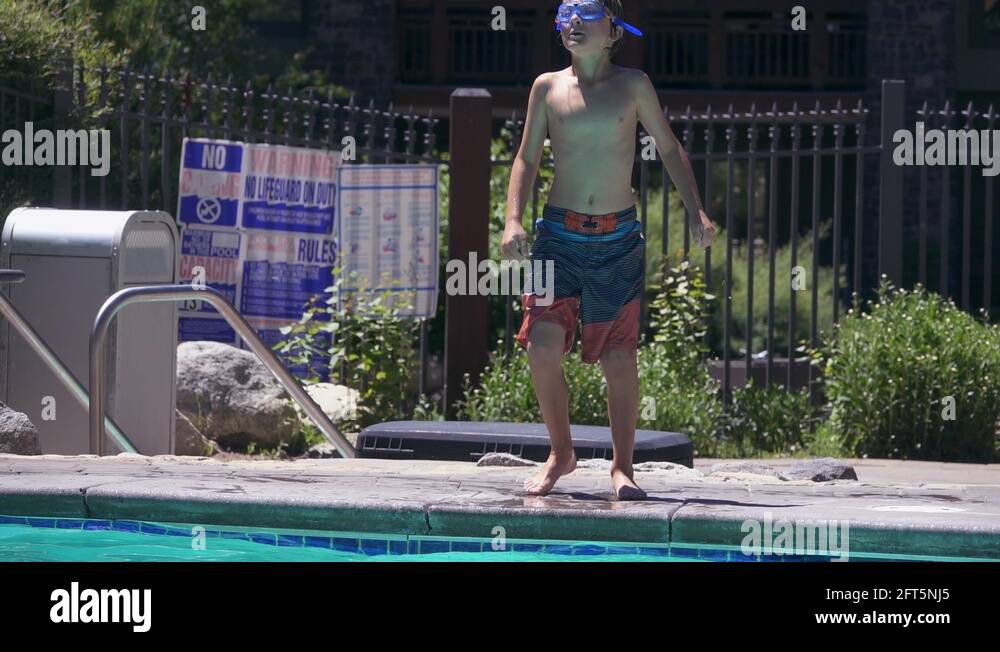A boy jumps and does a cannonball into a pool at a hotel resort Stock ...
