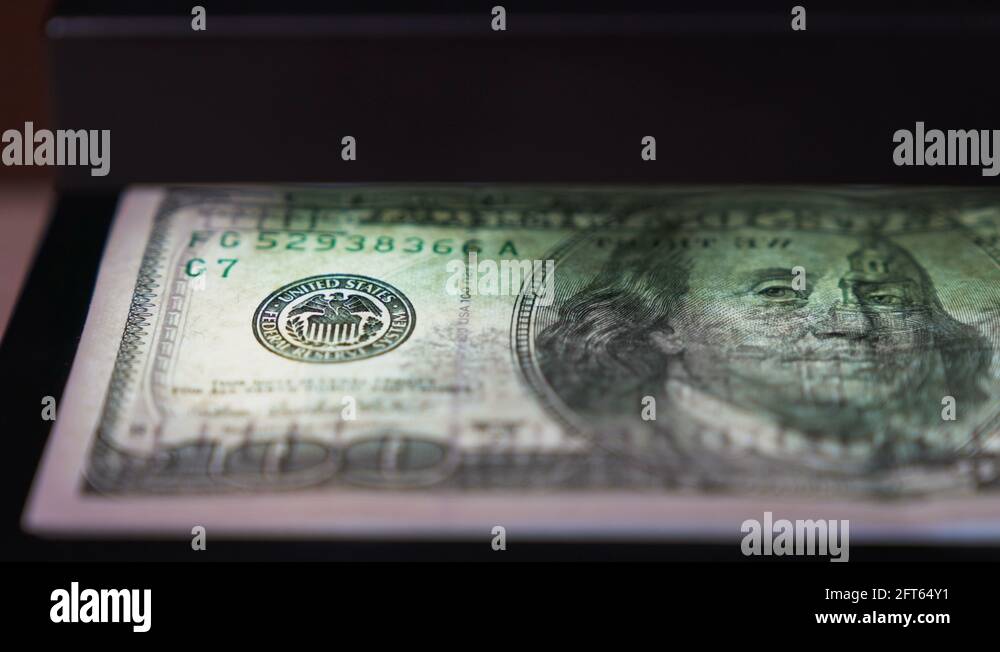 Cash checking machine with 100 dollar bill under ultraviolet light ...
