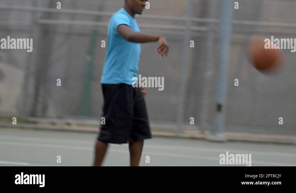 Two young men shooting hoops together on an outdoor basketball court ...