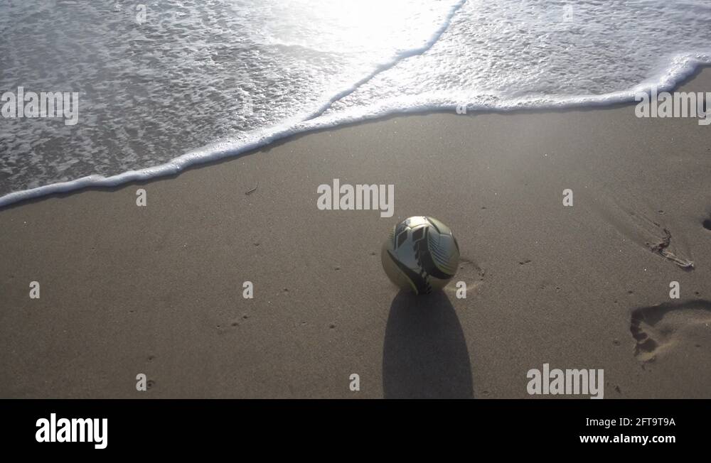 POV of a soccer ball being kicked in the waves surf at the beach Stock ...