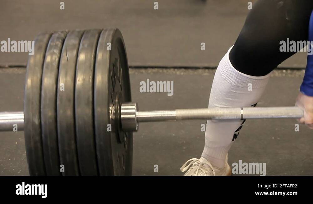 A male muscular athlete performing pull ups with heavy weights on his ...