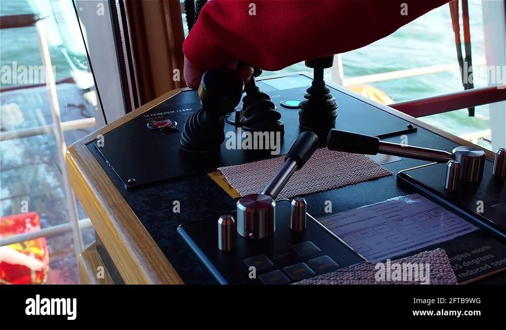 Man's hand in a red dress winch control lever on the bridge of the ship ...