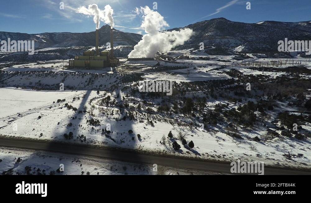 Aerial Back lit steam rises from coal fired power plant cold winter ...