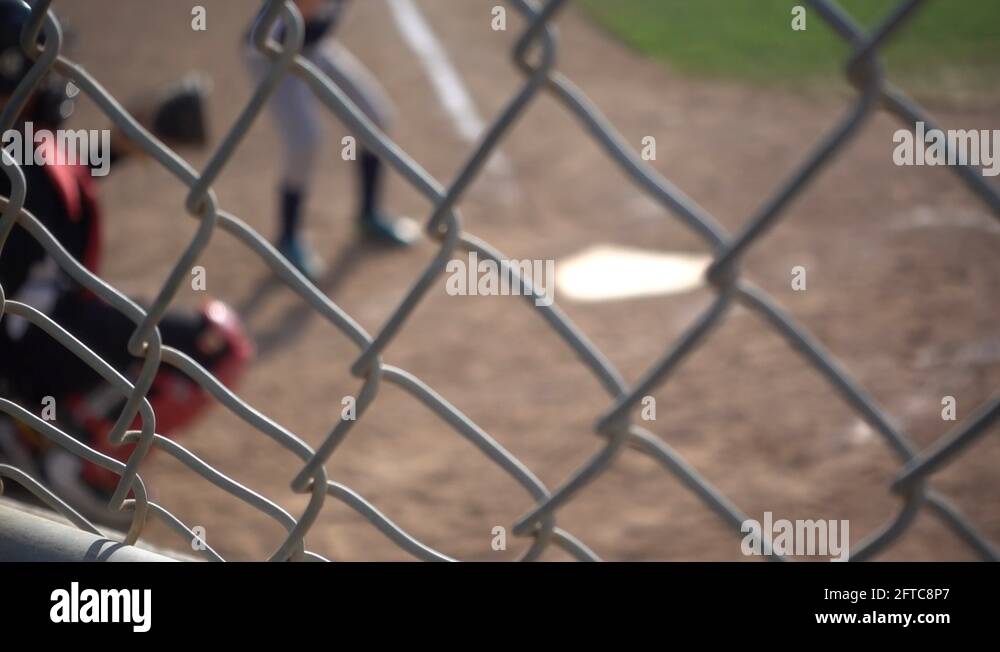 Boys playing in a little league baseball game through a chain-link ...