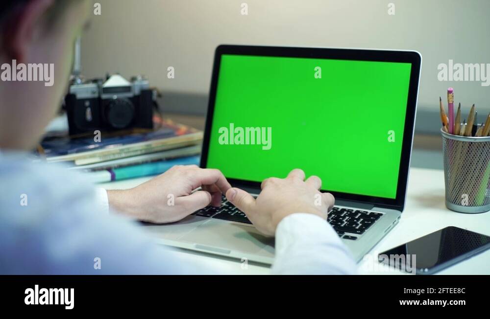 A man types on a laptop on his desk. Green screen for your custom ...