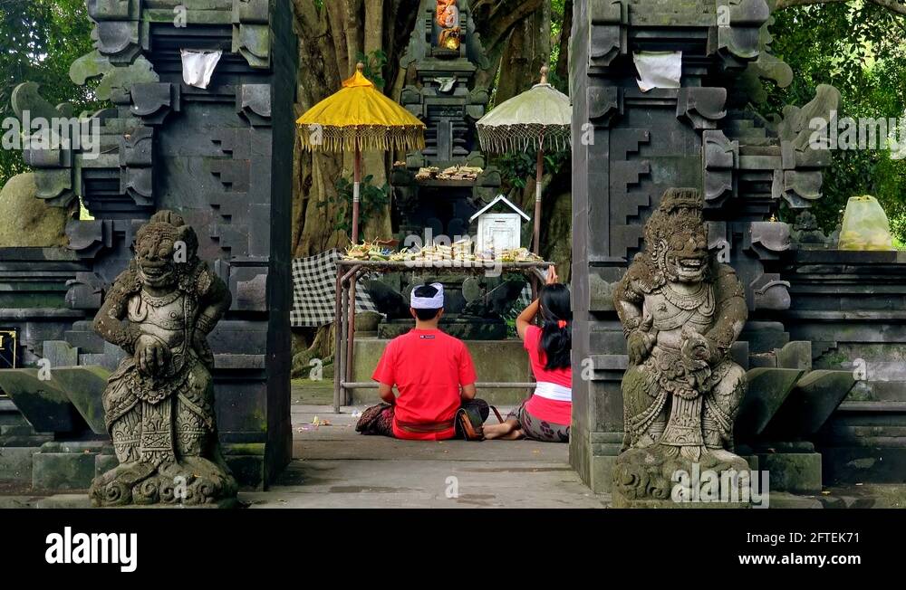 Young couple making offerings and praying at Gunung Kawi Temple. Bali ...