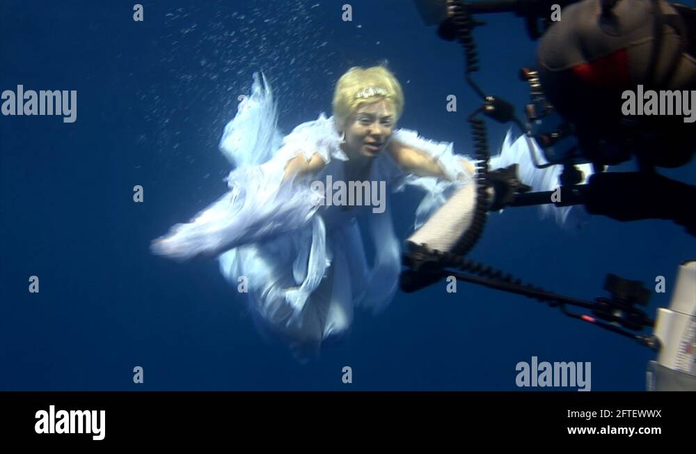 Underwater model free diver in costume angel swims in clean water in ...