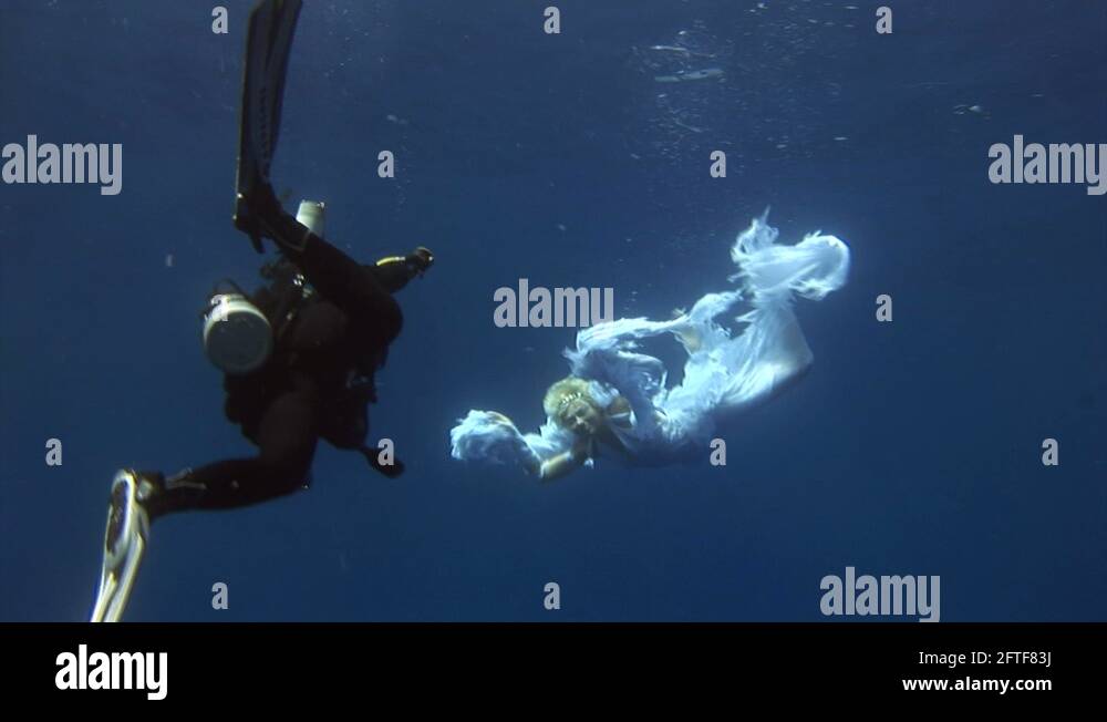 Underwater model free diver in costume angel swims in clean water in ...