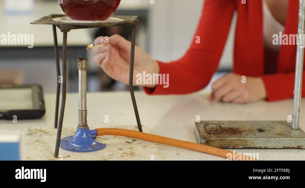 4K Teacher in school science class lighting Bunsen burner under flask ...