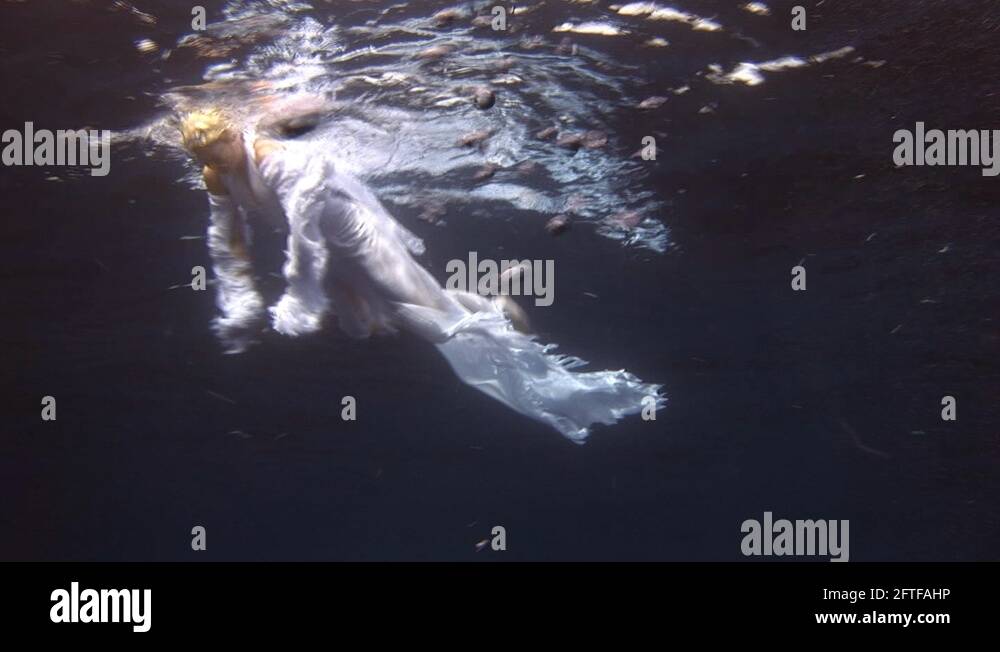 Underwater model free diver in costume angel swims in clean water in ...