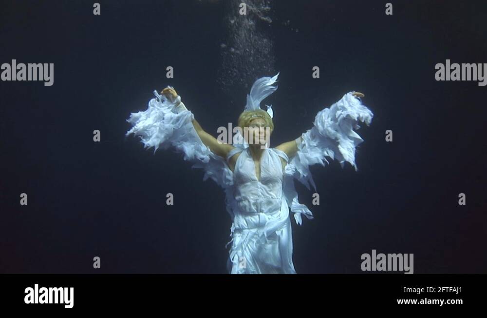 Underwater model free diver in costume angel swims in clean water in ...