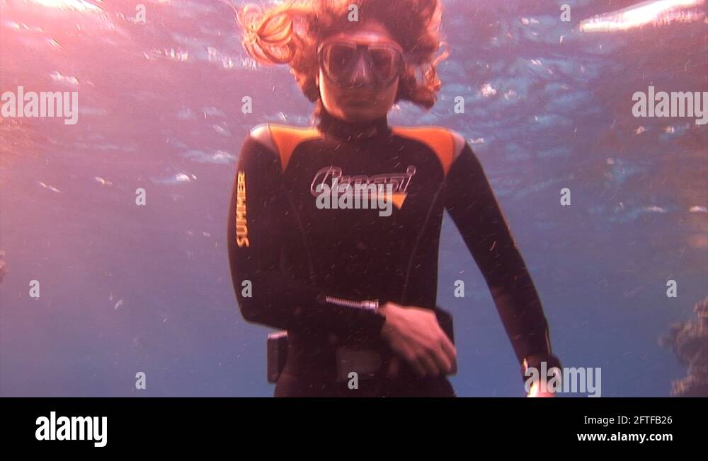 Underwater model free diver swims in clean transparent blue water in ...