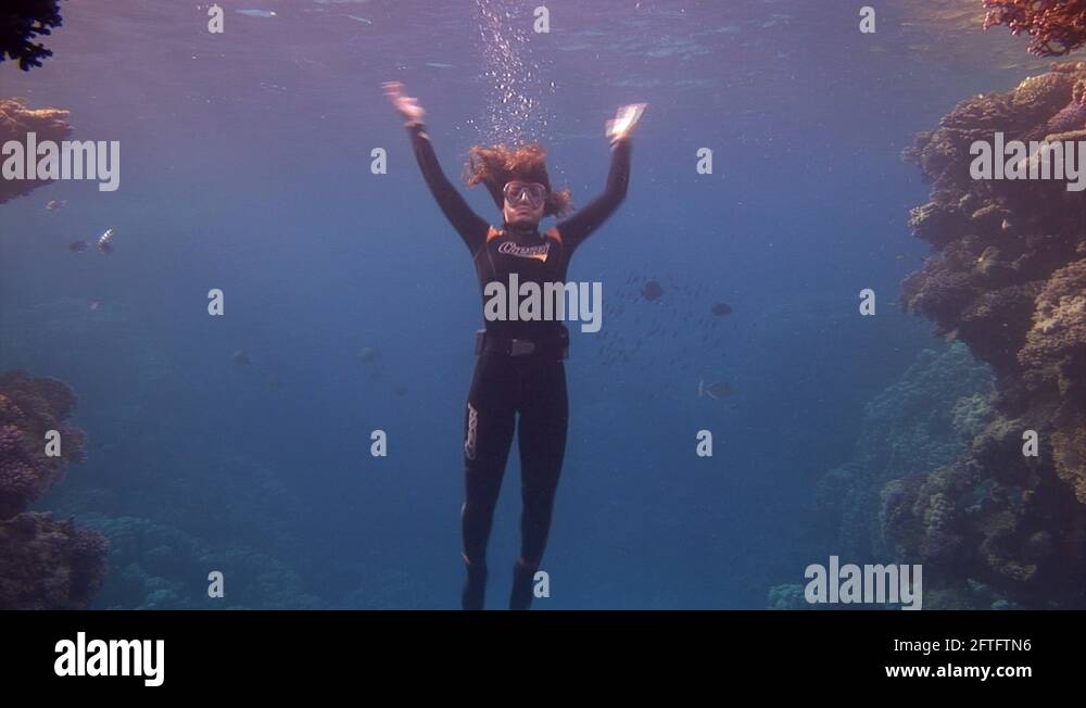 Underwater model free diver poses for the camera in clean blue water in ...
