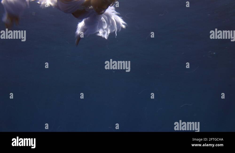 Underwater model free diver in costume angel swims in clean water in ...