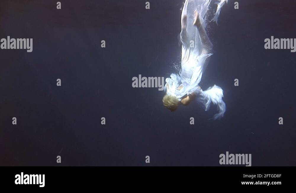 Underwater model free diver in costume angel swims in clean water in ...