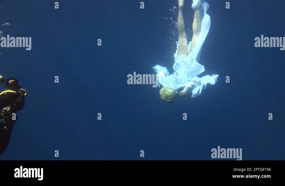 Underwater model free diver in costume angel swims in clean water in ...