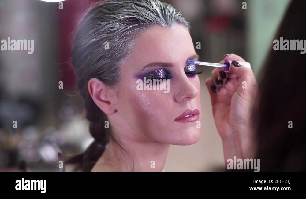 Draw eyebrows. Makeup artist apply makeup to an attractive young model ...