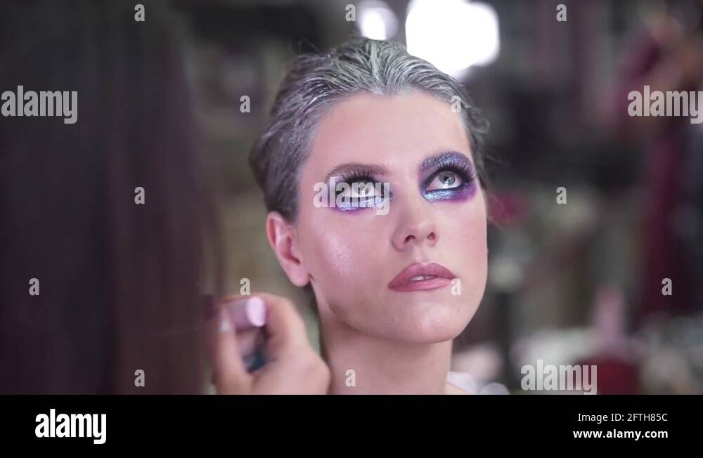 Draw eyebrows and eyes. Makeup artist apply makeup to an attractive ...