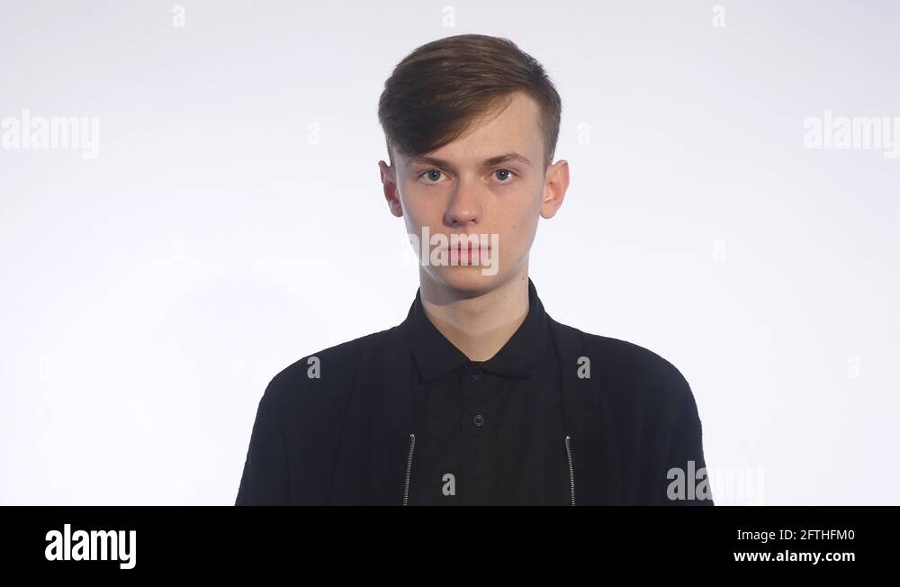 Handsome young man standing against white background and showing ...