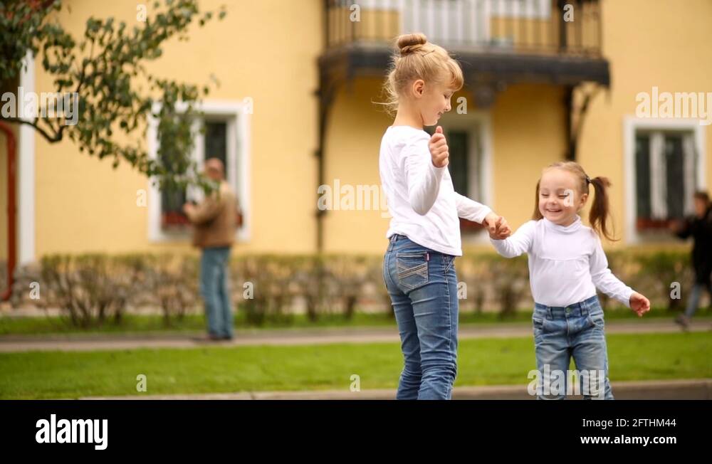 Two girls on roller skates holding hands on the street in summer day ...
