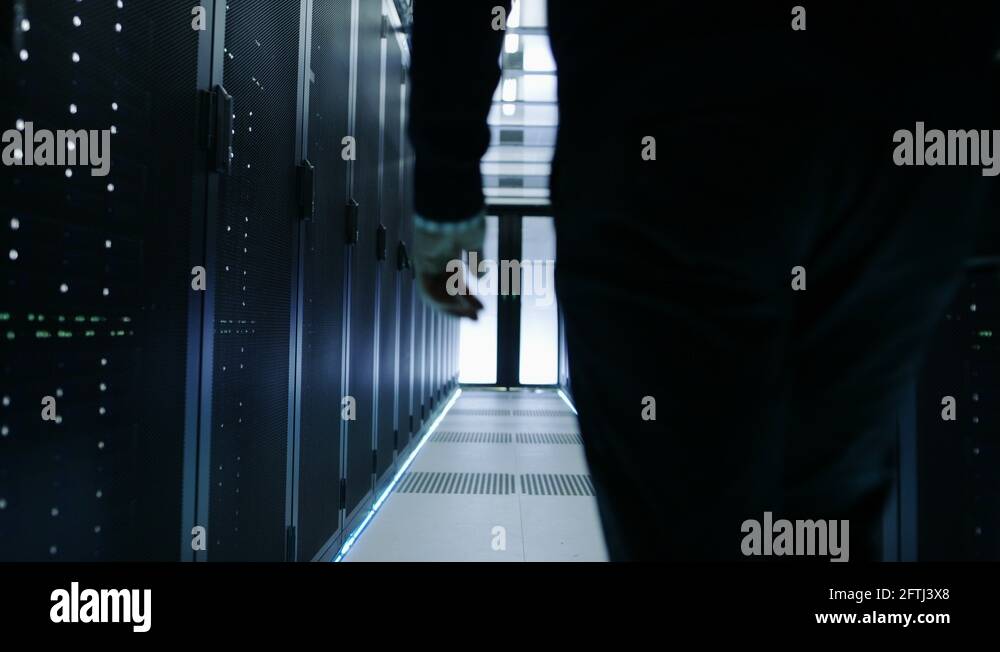 Back View of IT Engineer Walking Through Data Center with Working Rack ...