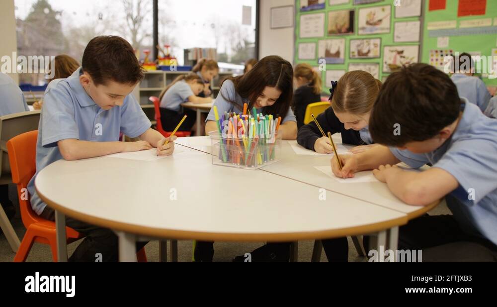 4K Young school children working in groups in classroom with teacher ...