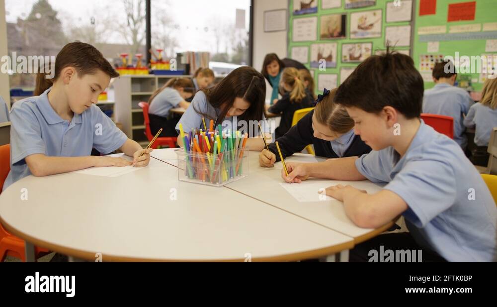 4K Young school children working in groups in classroom with teacher ...