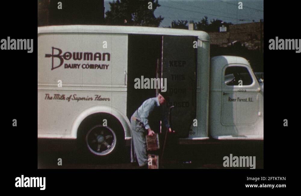 1940s: A milkman removes crates of dairy products from a parked milk ...