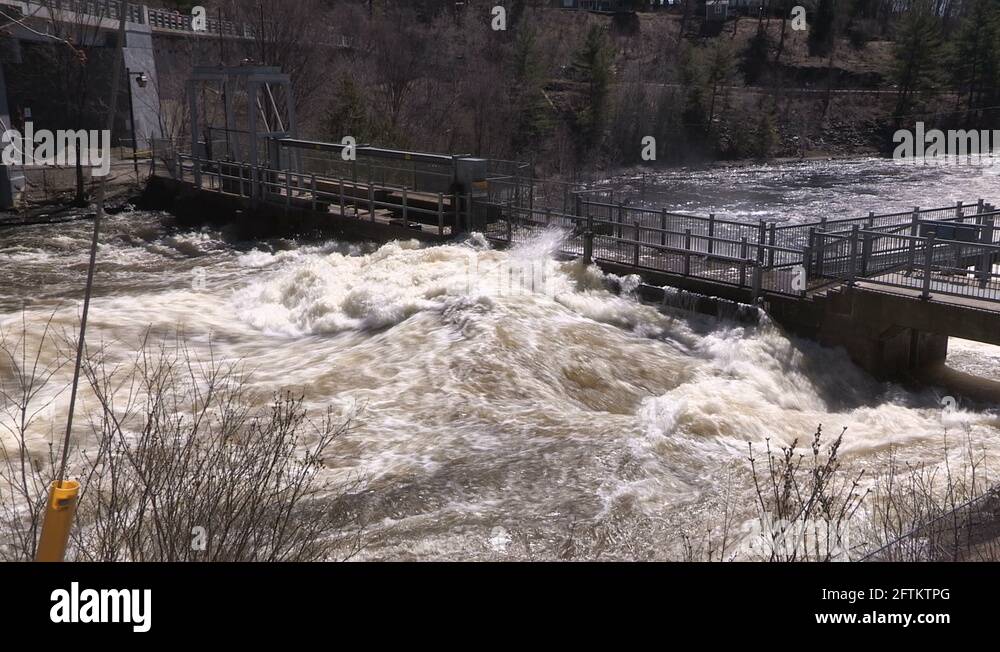 Dangerous flooding water over top of dam infrastructure during spring ...