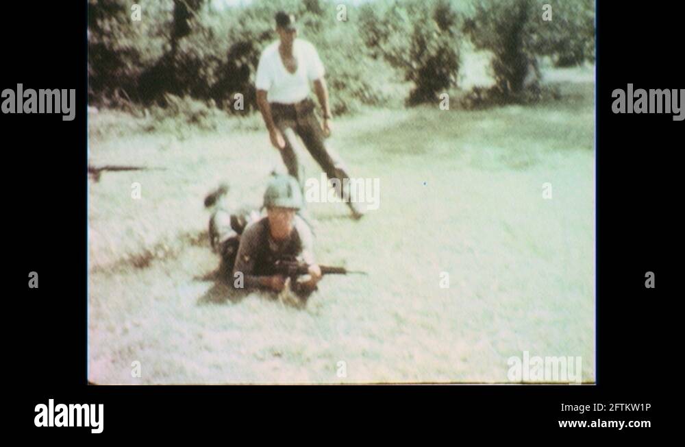 1960s: Officer with soldier, soldier drops to ground / Soldiers crawl ...